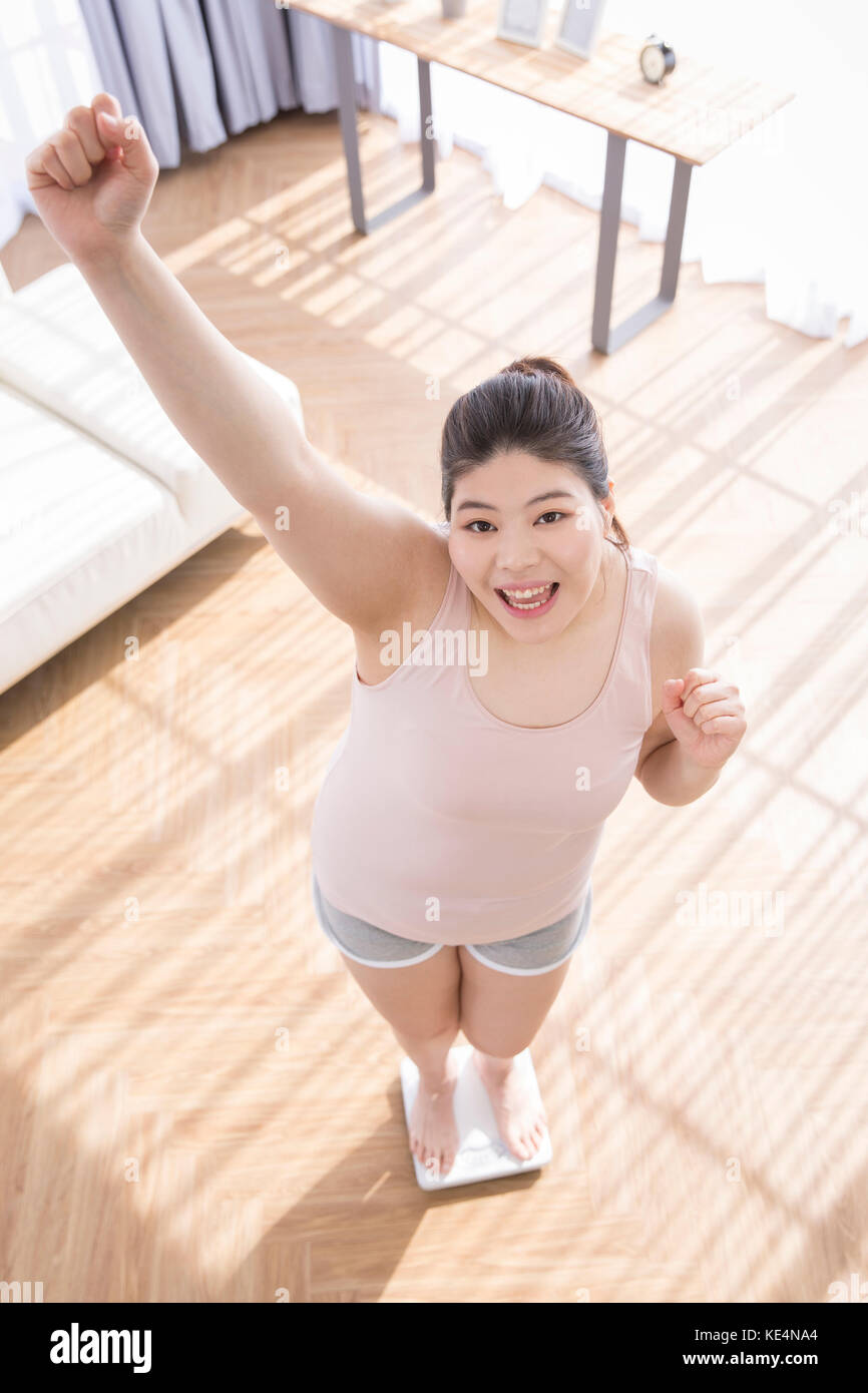 Young smiling slim woman cheering standing on a scale Stock Photo - Alamy
