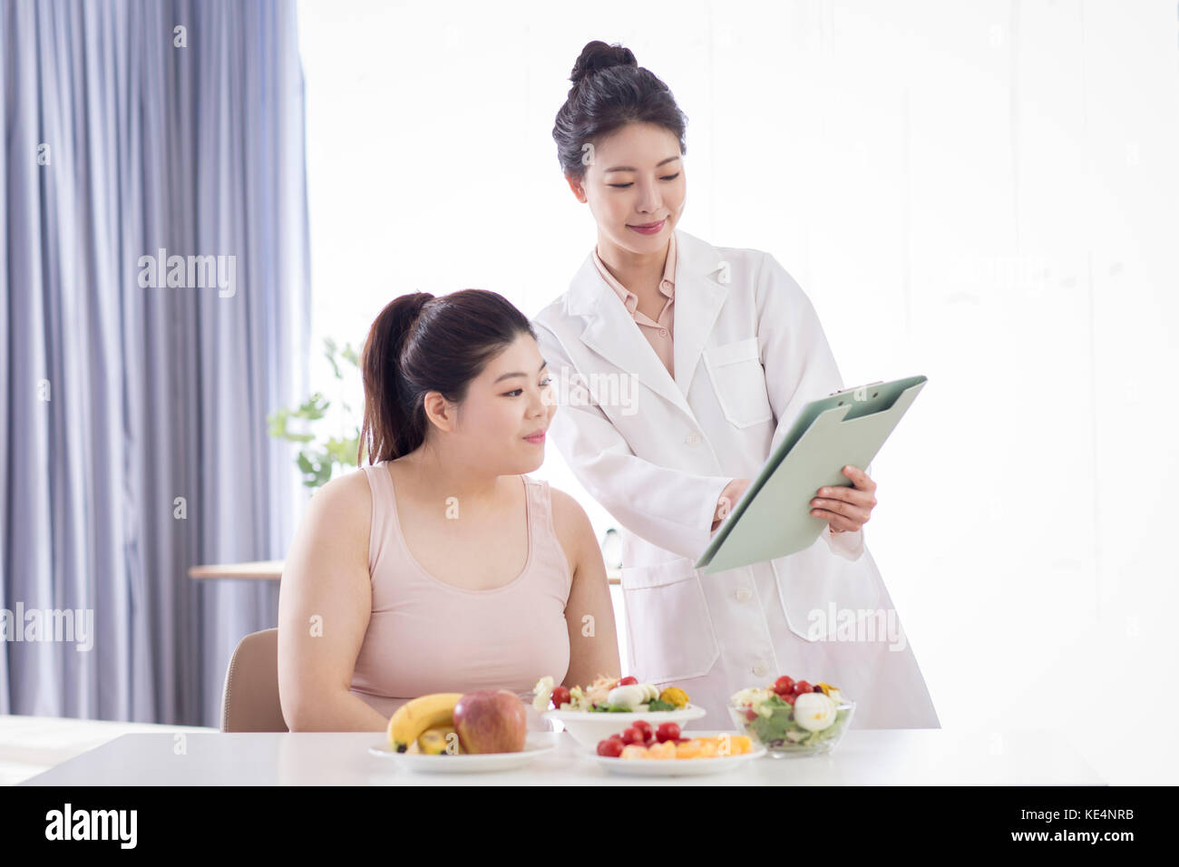 Smiling nutritionist advising a young fat woman on diet Stock Photo - Alamy