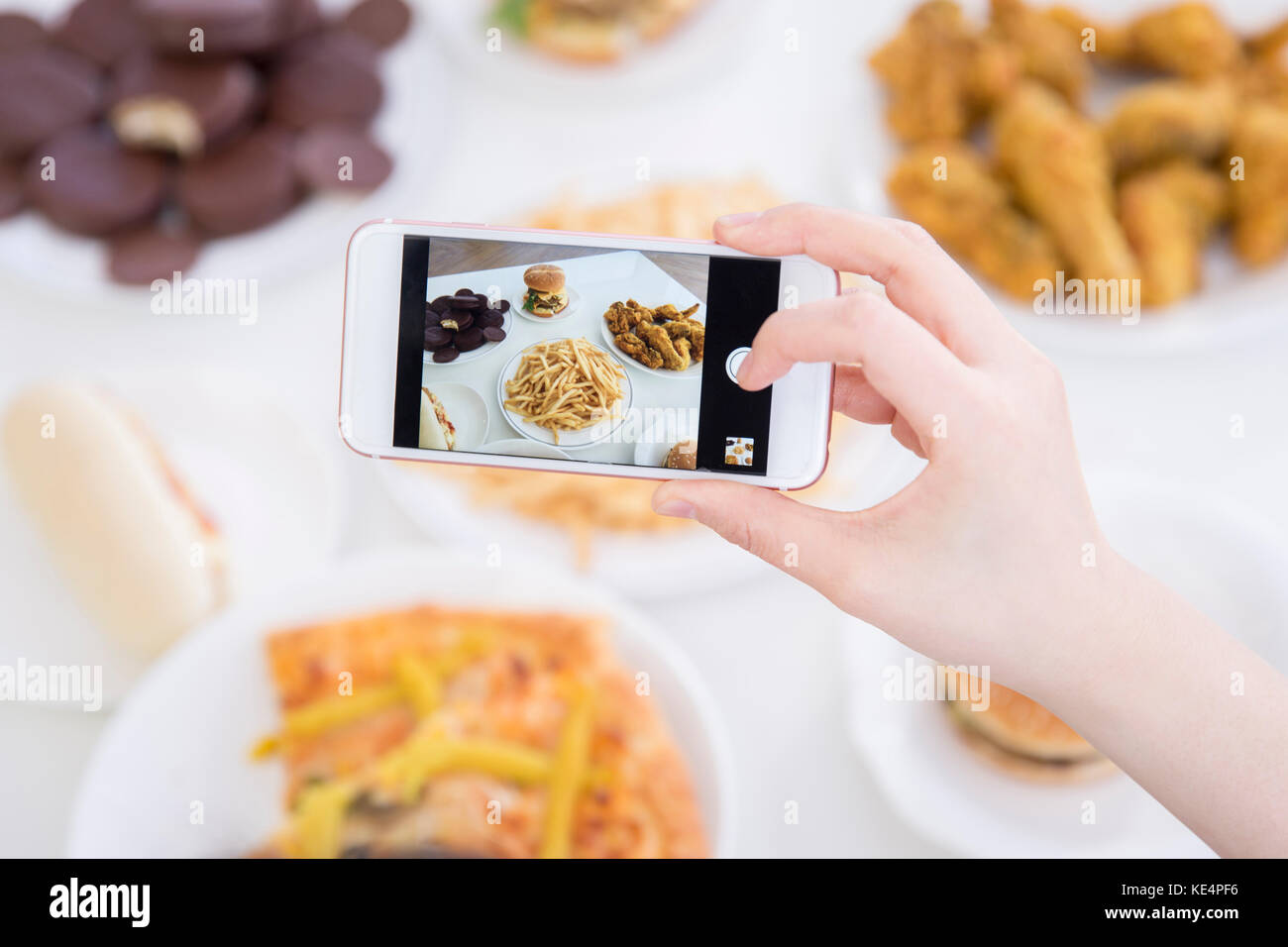 Hand holding a.smartphone for photos of fast-food and sweets Stock ...