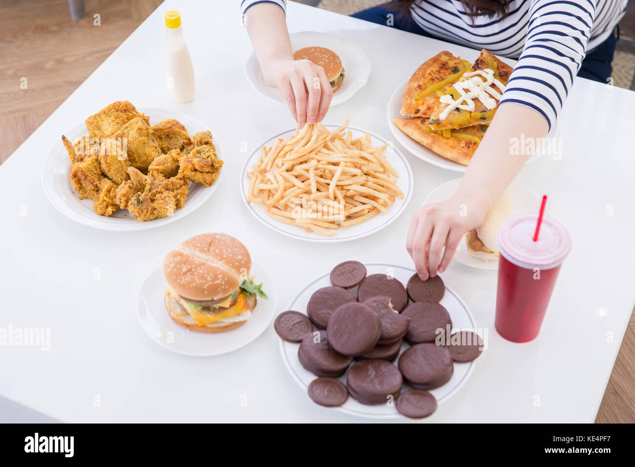 Woman holding fast-food and sweets Stock Photo - Alamy
