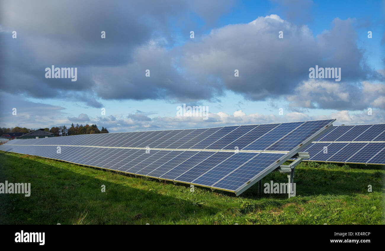 Solar panel or photovoltaic farm on green field with dramatic cloudy ...