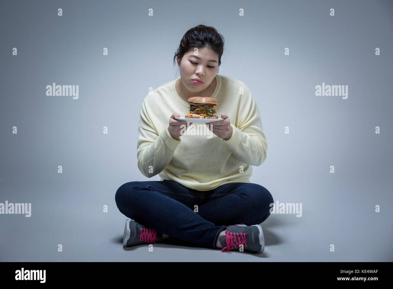 Young fat woman tempted by fast-food Stock Photo - Alamy