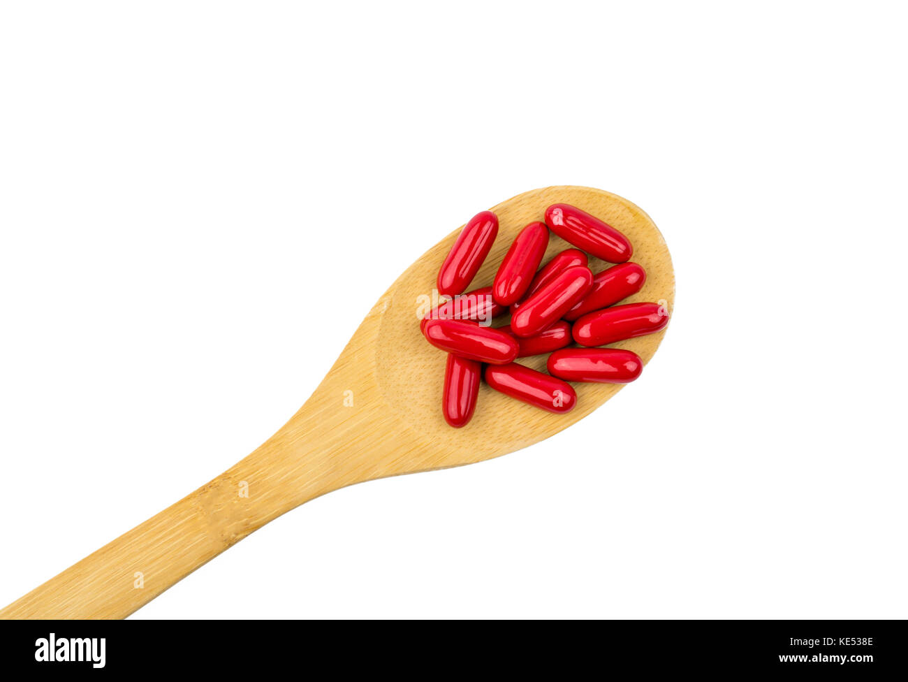 Red vitamins and supplements capsule on wooden spoon isolated on white ...