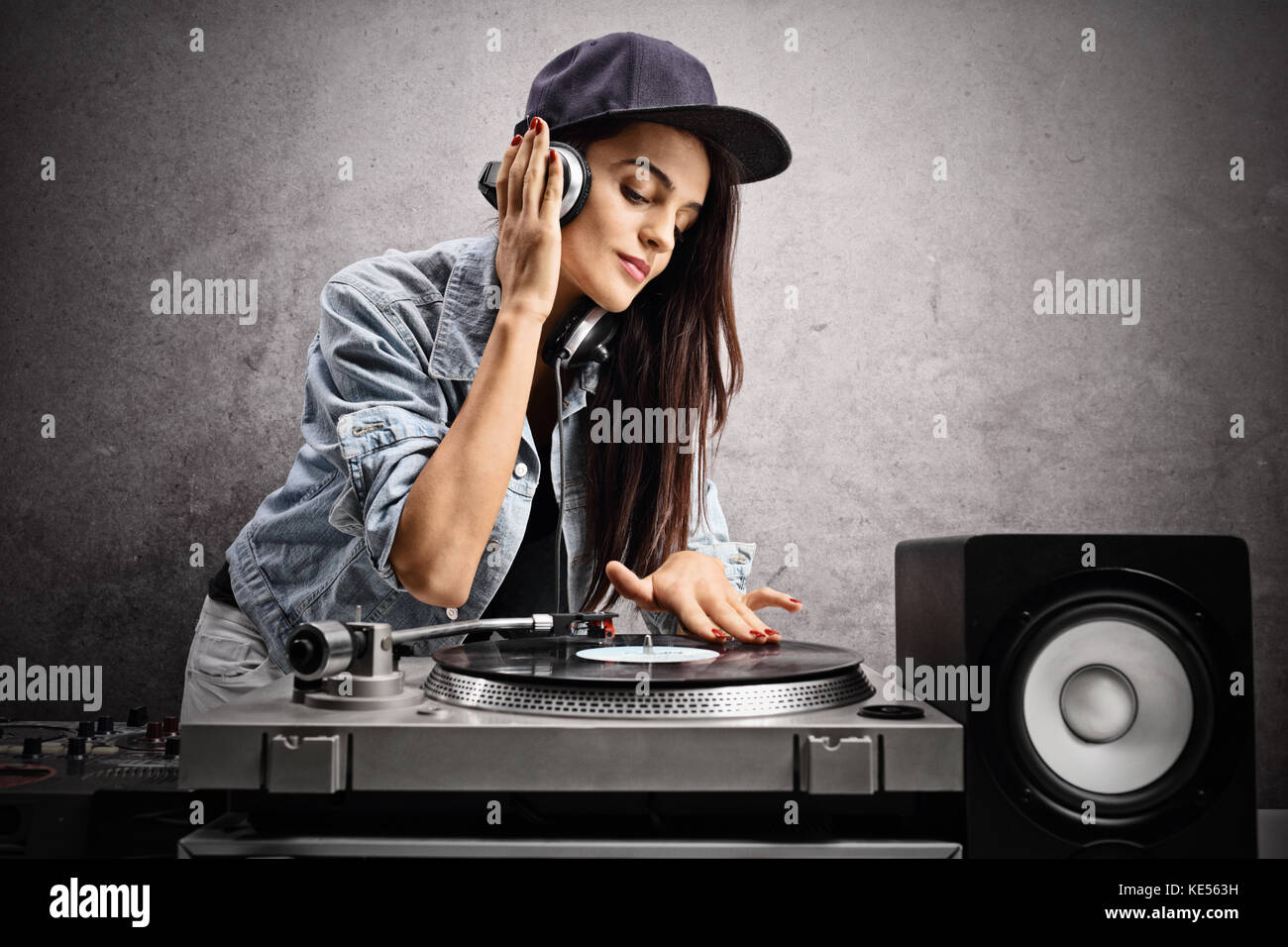 Female DJ playing music on a turntable against a rusty gray wall Stock ...