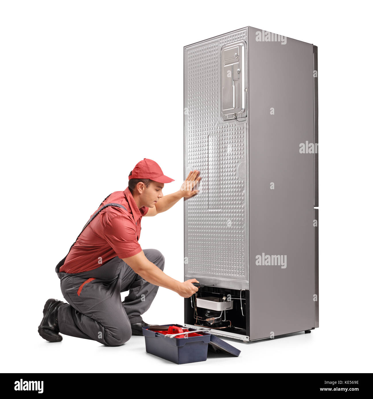 Young repairman fixing a refrigerator isolated on white background ...