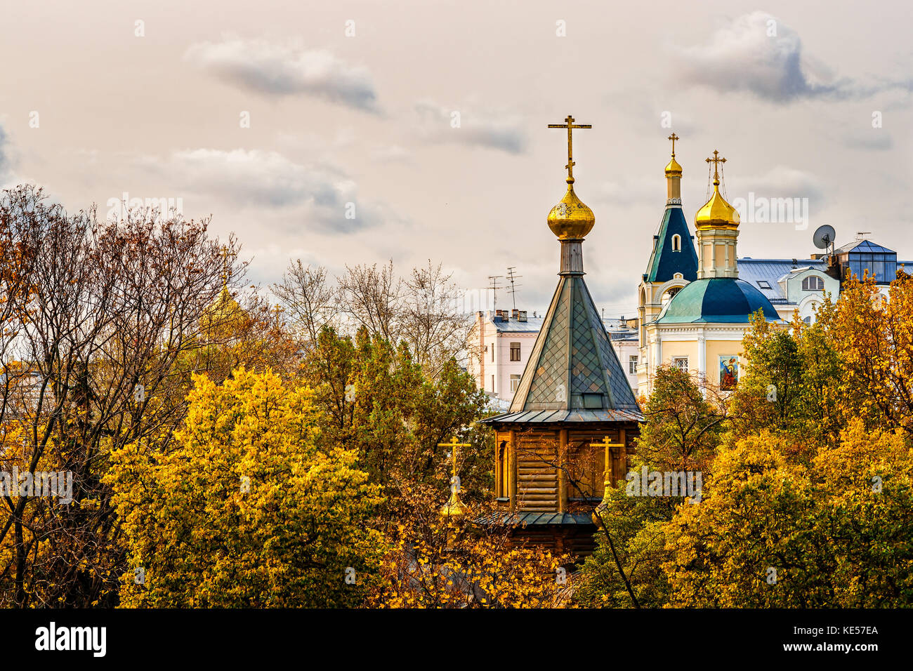 View of a small wooden church in the big city in the golden autumn ...