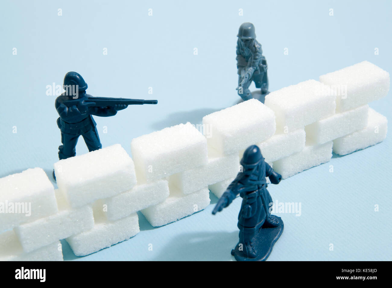 Battlefield with plastic soldiers separated by a wall border of white ...