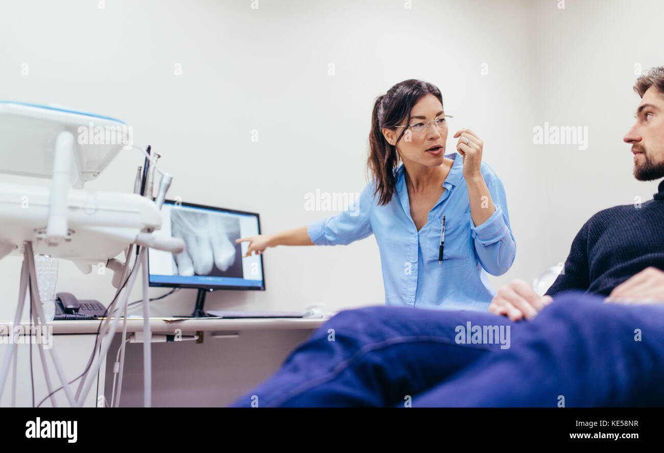 Dentist showing patient the x-ray image of teeth on computer monitor ...