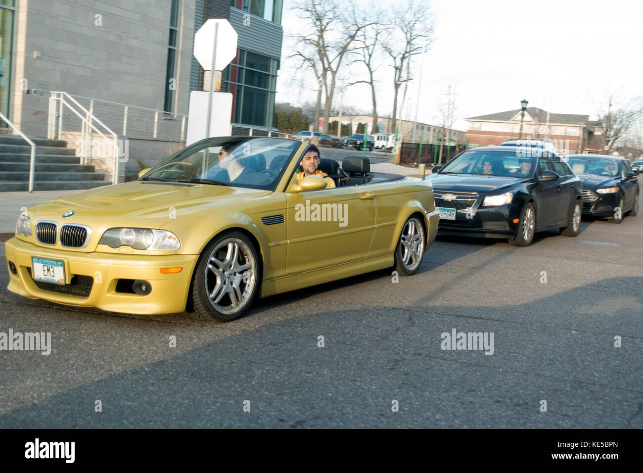 Good looking mustard colored BMW convertible sports car driven by two ...
