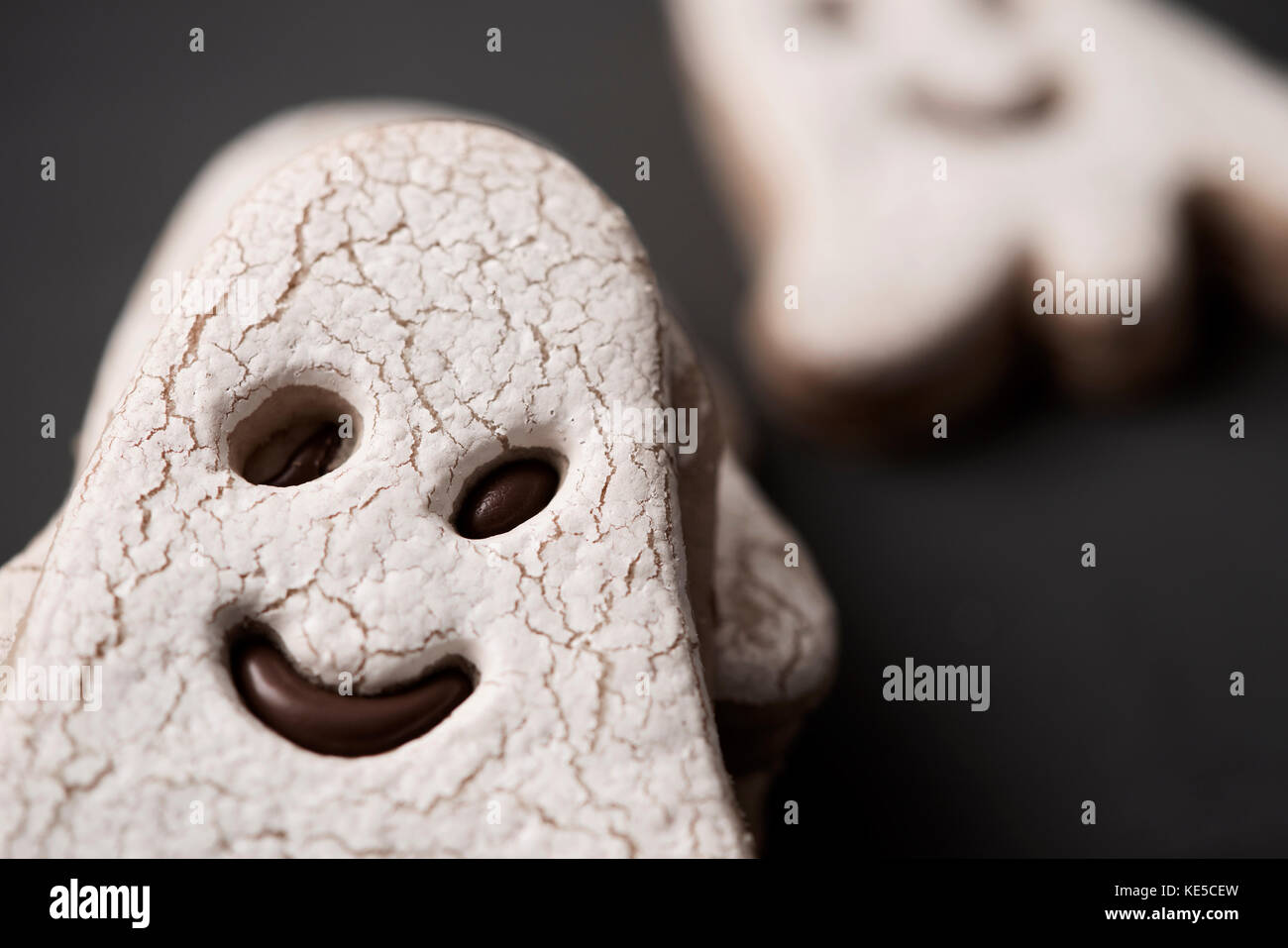 closeup of some cookies in the shape of a ghost, on a dark gray surface ...