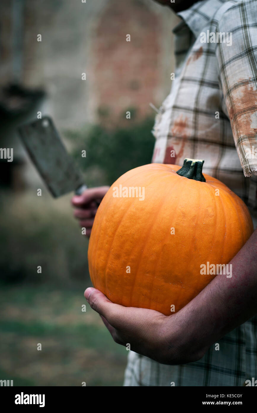 closeup of a scary man wearing dirty and ragged clothes with a pumpkin ...