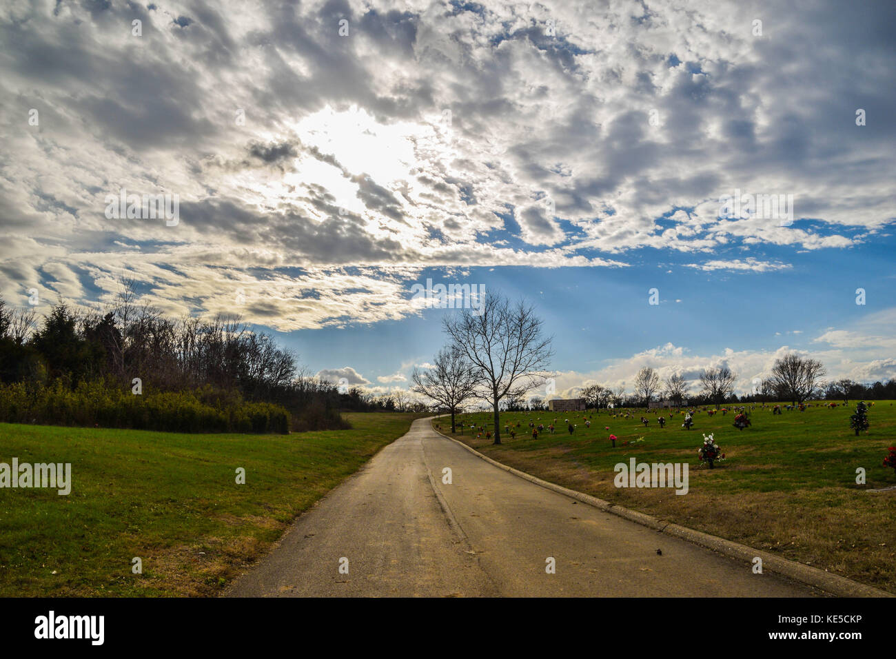 Clouds over long road in cemetery Stock Photo - Alamy