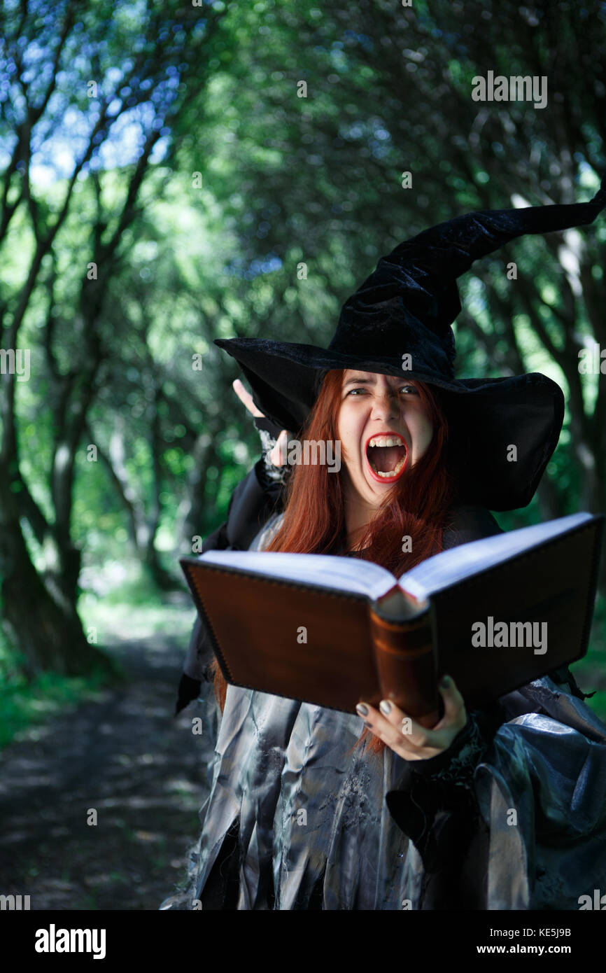 Image of young screaming witch with magic book in mystical forest Stock ...