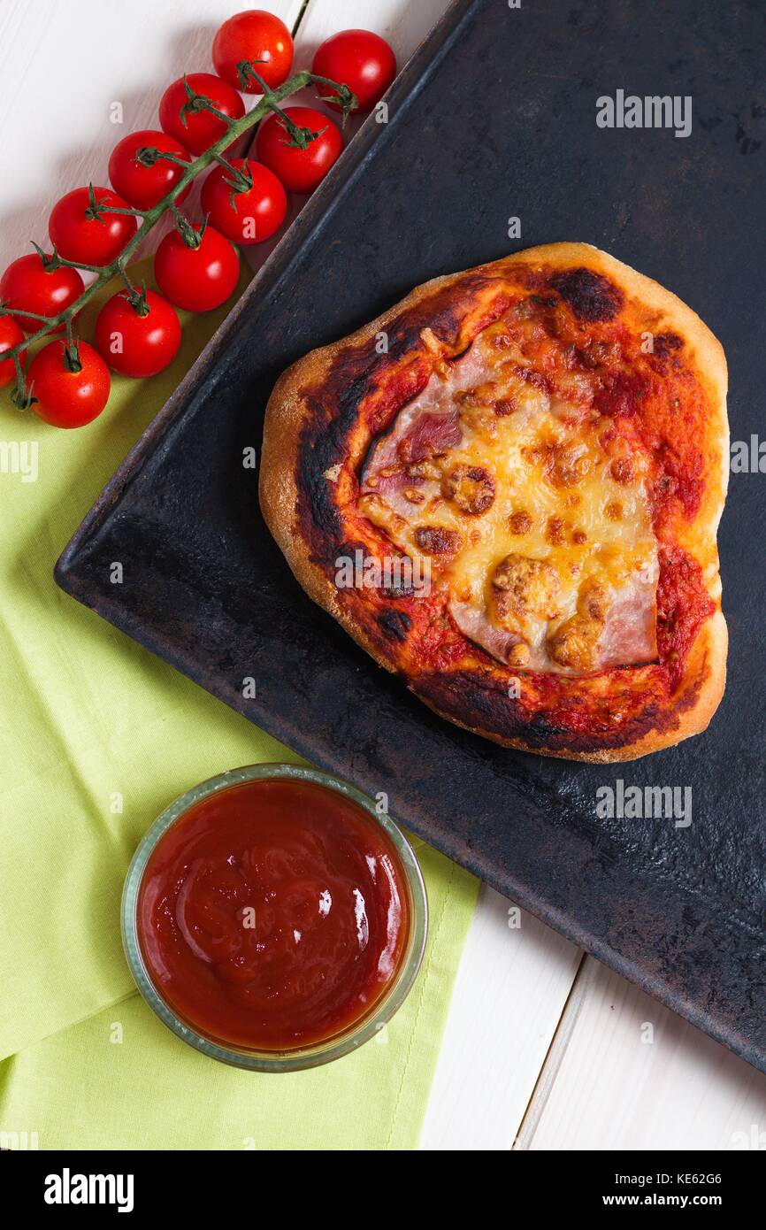 Top down view on homemade pizza, imperfectly shaped and well done with ...