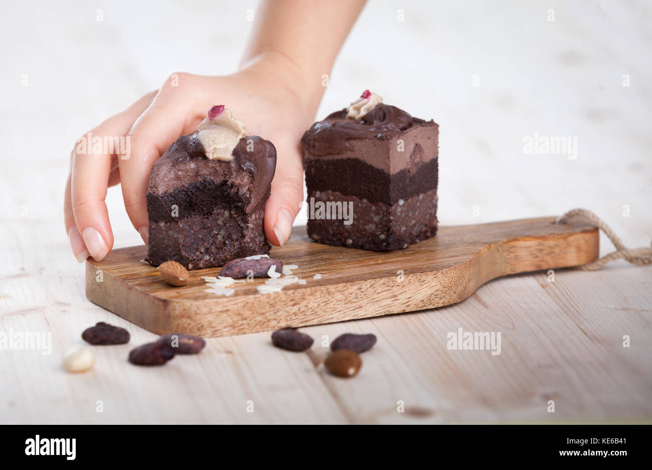 A hand placing back a delicious raw vegan cake which has been bitten ...
