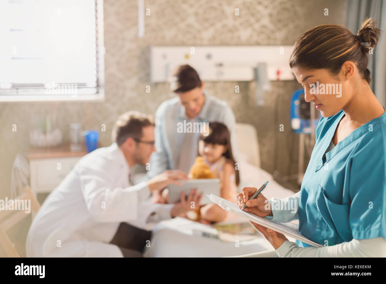 Female nurse taking notes on medical record clipboard while doctor ...