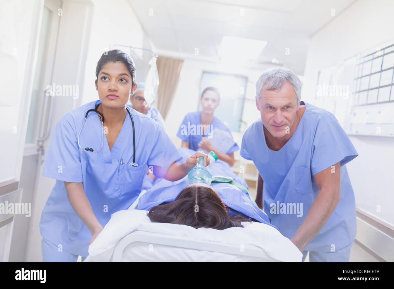 Determined surgeons pushing female patient on stretcher down hospital ...