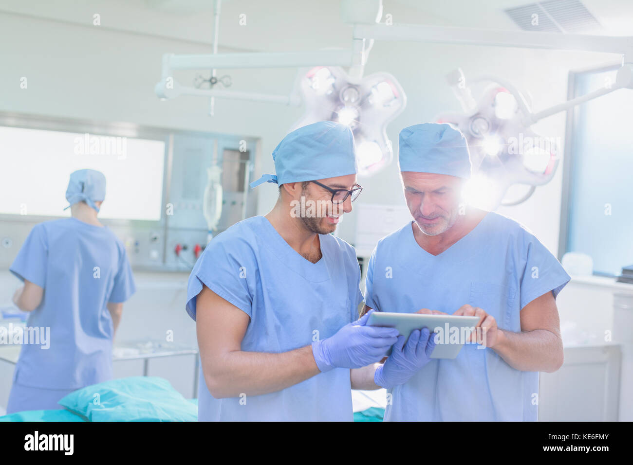 Male surgeons talking, using digital tablet in operating room Stock ...