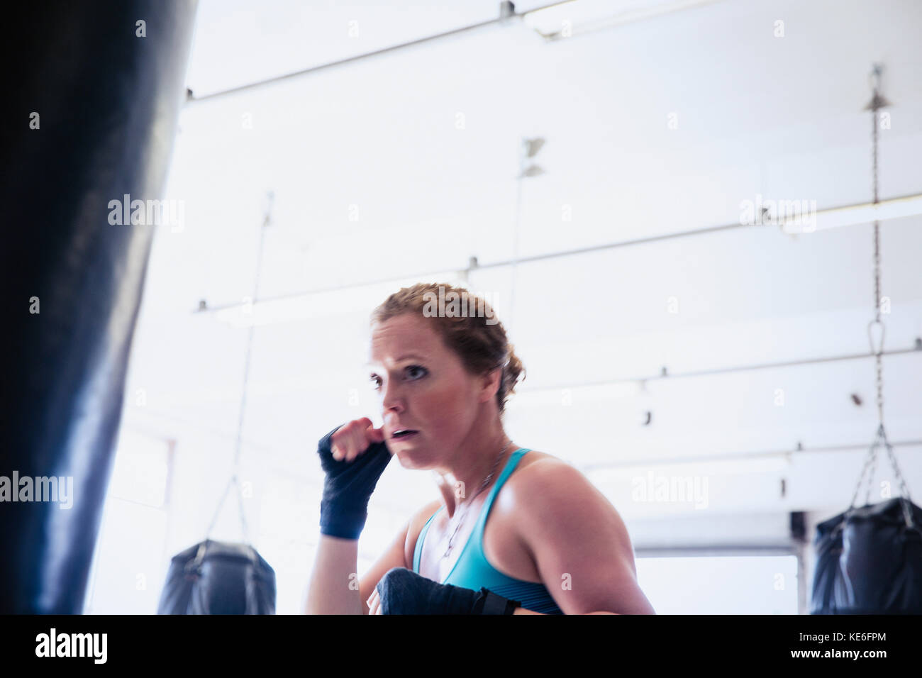 Determined female boxer boxing at punching bag in gym Stock Photo - Alamy