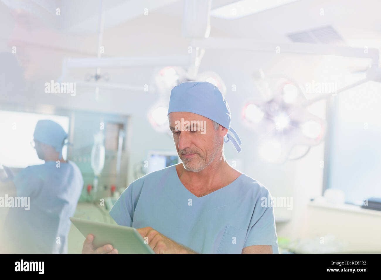 Mature male surgeon using digital tablet in operating room Stock Photo ...