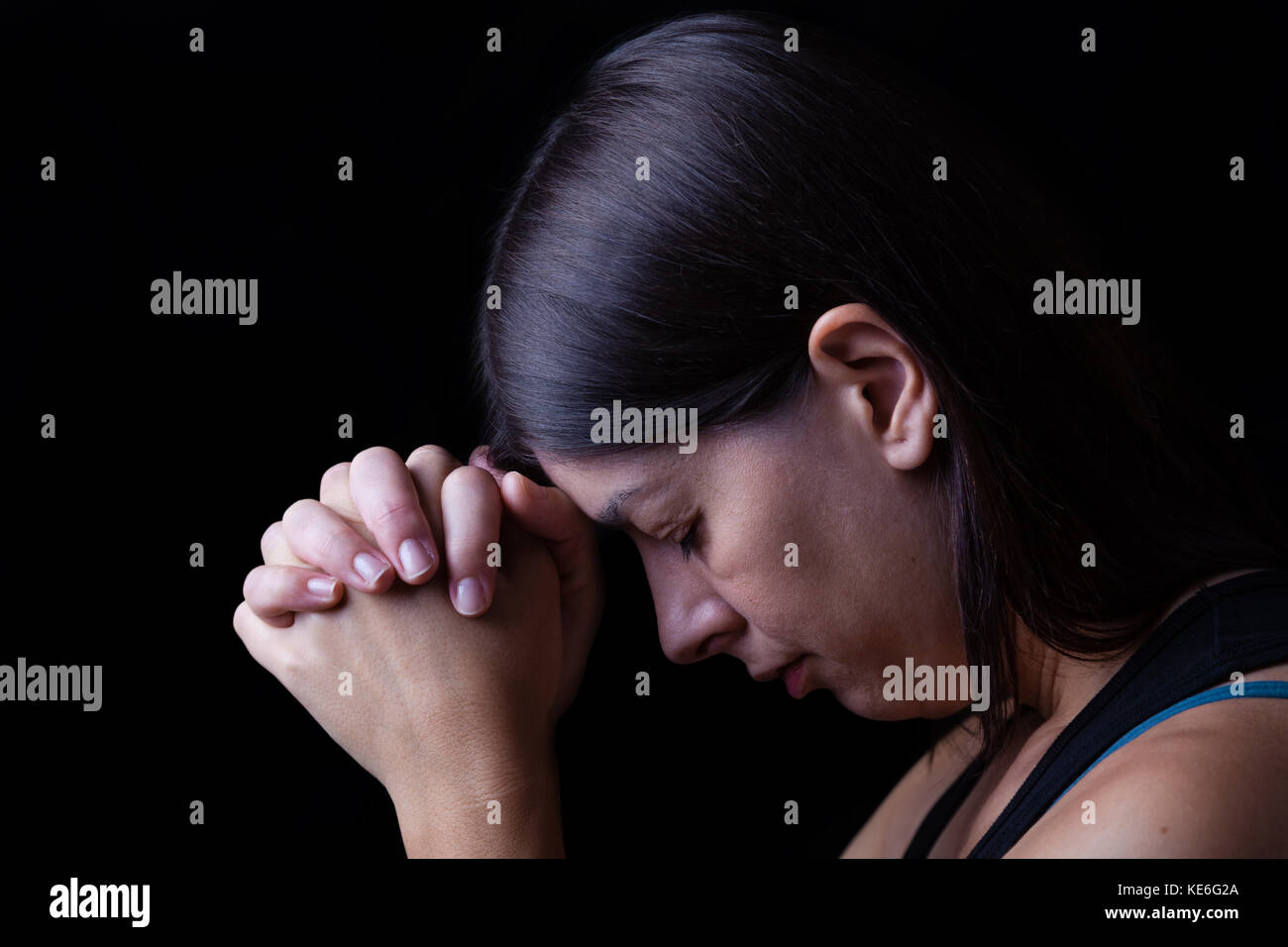 Faithful woman praying, hands folded in worship to god, head down, eyes ...