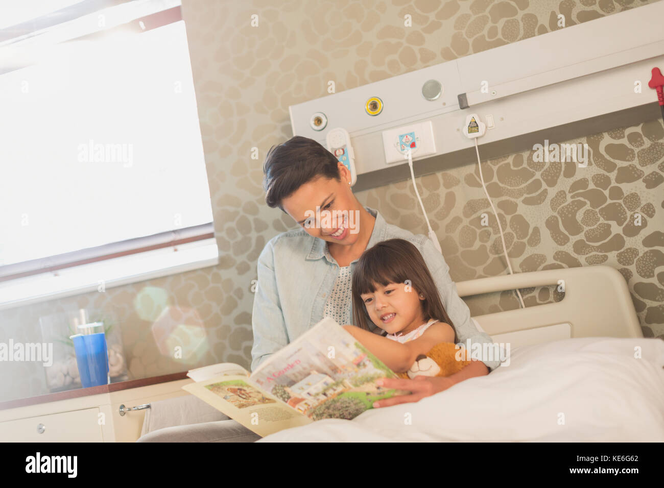 Mother reading book with daughter patient in hospital room Stock Photo ...