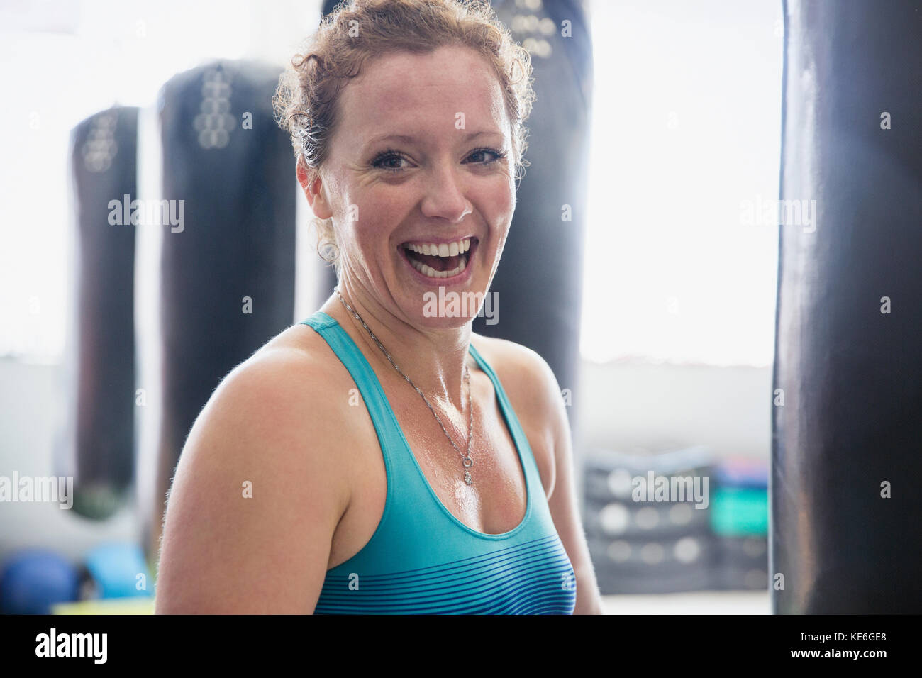 Portrait laughing female boxer standing at punching bag in gym Stock ...