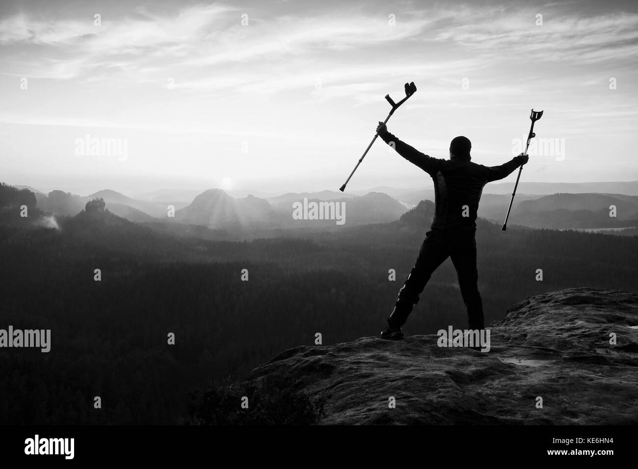 Tourist with forearm crutch above head achieved mountain peak. Hiker ...