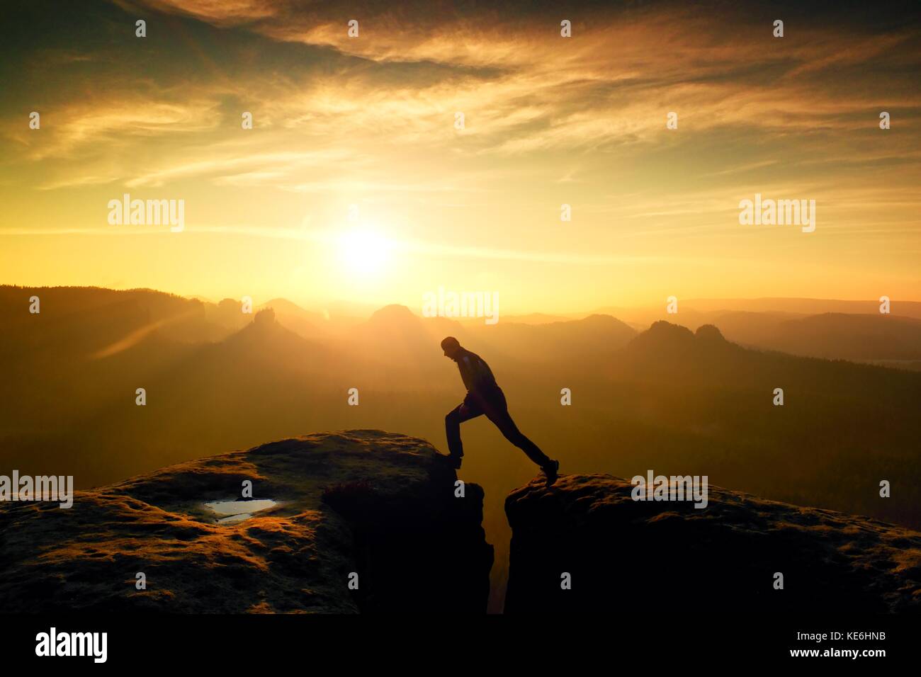 Crazy hiker in black is jumping between rocky peaks. Happy man ...