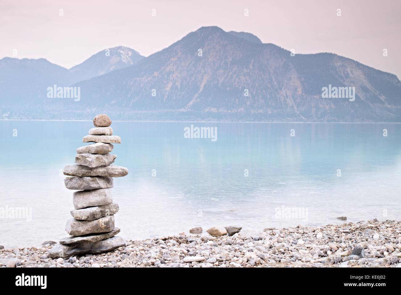 Balanced stone pyramide on shore of blue water of mountain lake. Blue ...