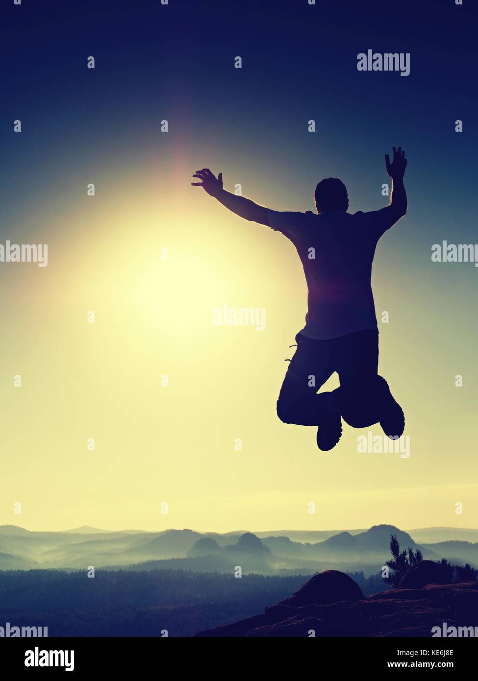 Jumping man. Young crazy man is jumping on colorful sky background ...