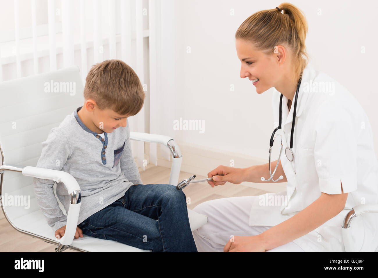 Happy Female Doctor Checking Knee Reflex On A Child Patient In Clinic ...