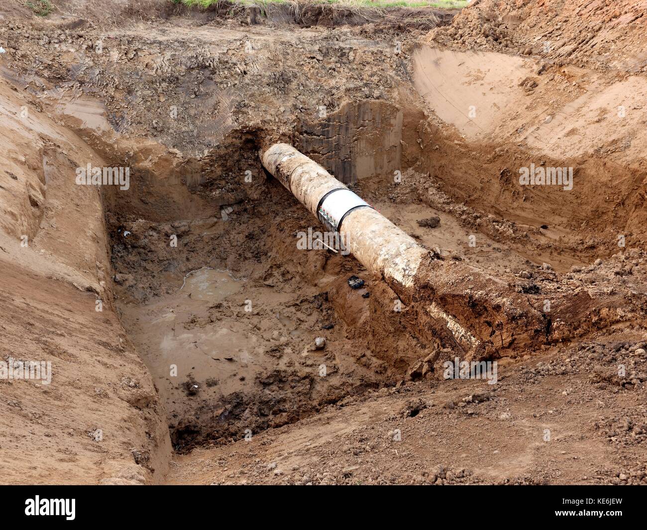Excavation pit. Old drink water pipe with stainless repairing sleeve ...