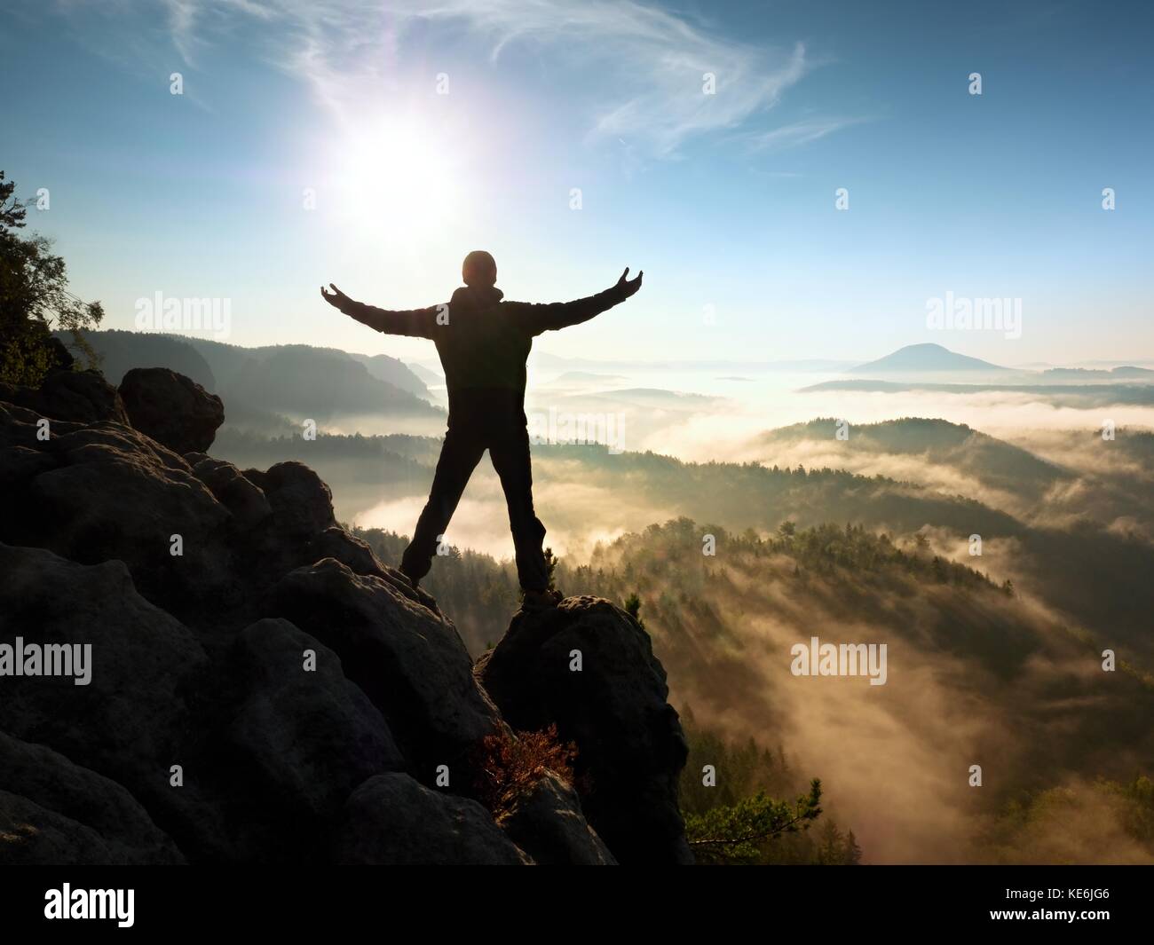 Sunny fall morning. Happy hiker with raised hands in air stand on rock ...
