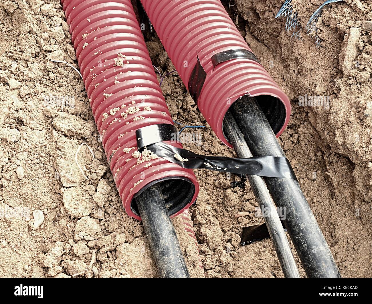 Excavation of trench with black cables in protective HDPE tube. Lines ...