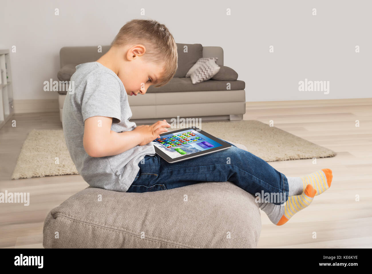 Boy Sitting On Cushion Playing Game On Digital Tablet Stock Photo - Alamy