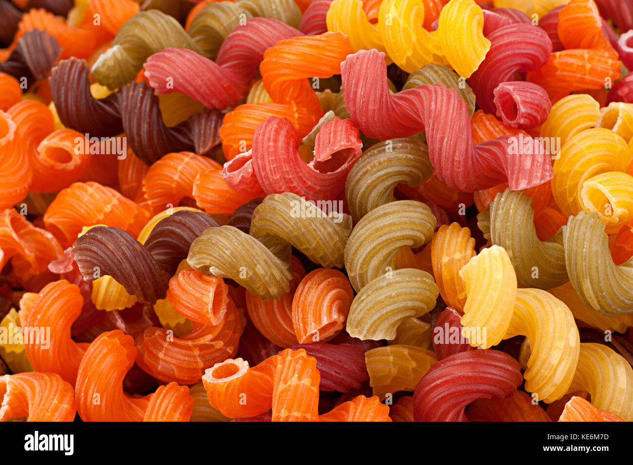Multicolor dry swirl pasta closeup view background Stock Photo - Alamy