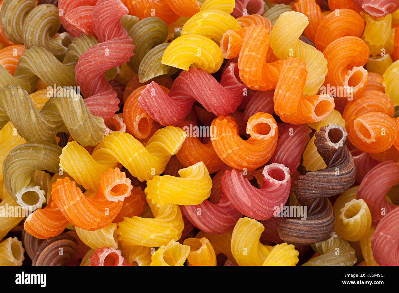 Multicolor dry swirl pasta closeup view background Stock Photo - Alamy