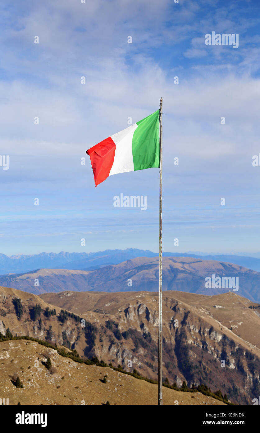 Italian flag waving high above the top of the mountain and the plain ...