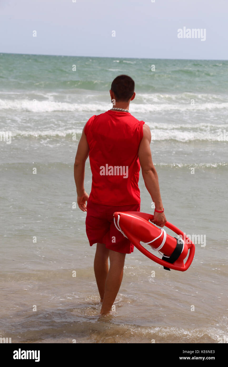 muscular lifeguard at shore at the sea shore in the beach of the ...