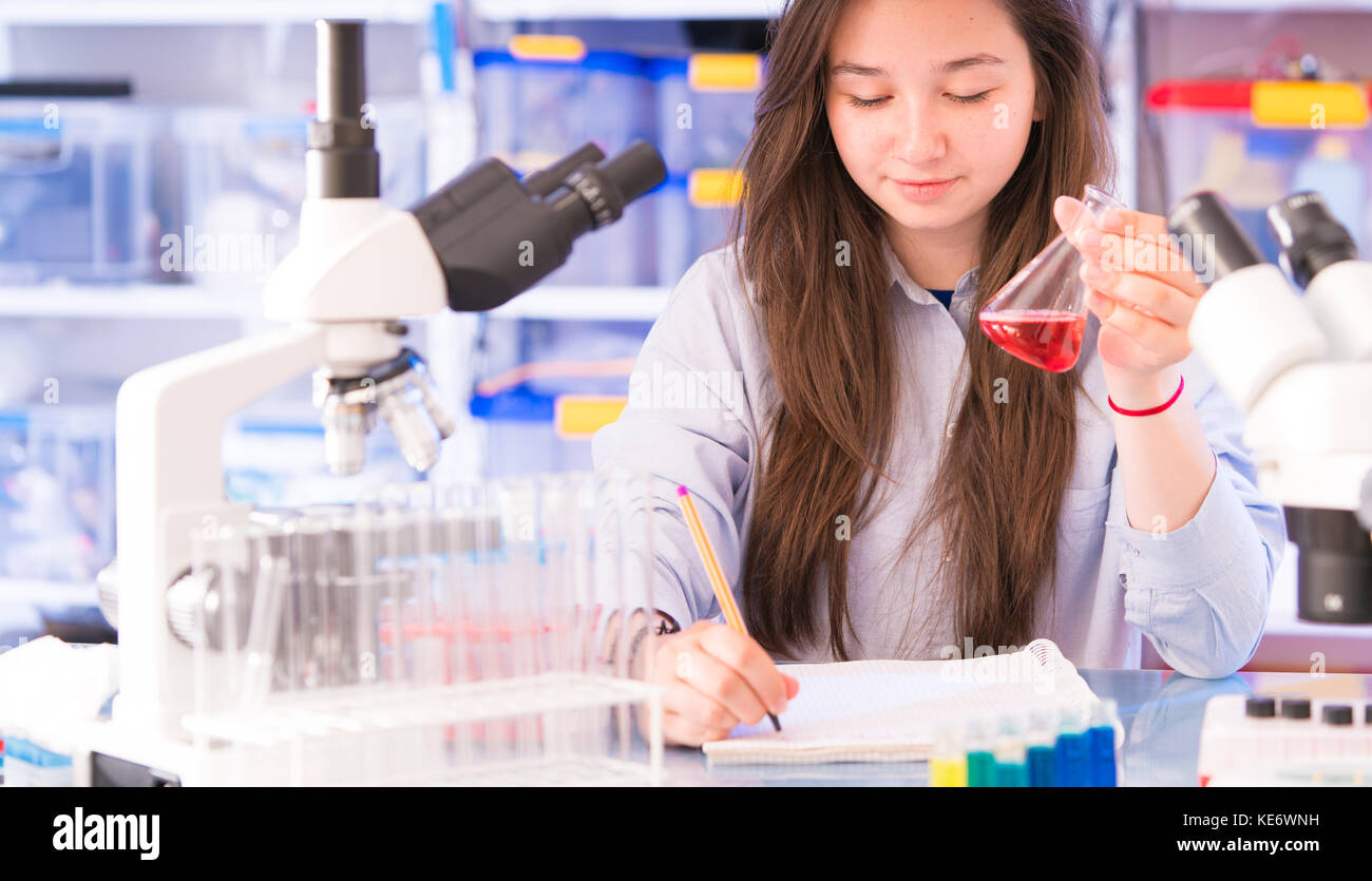 A teenage girl in a school laboratory in chemistry and biology classes ...
