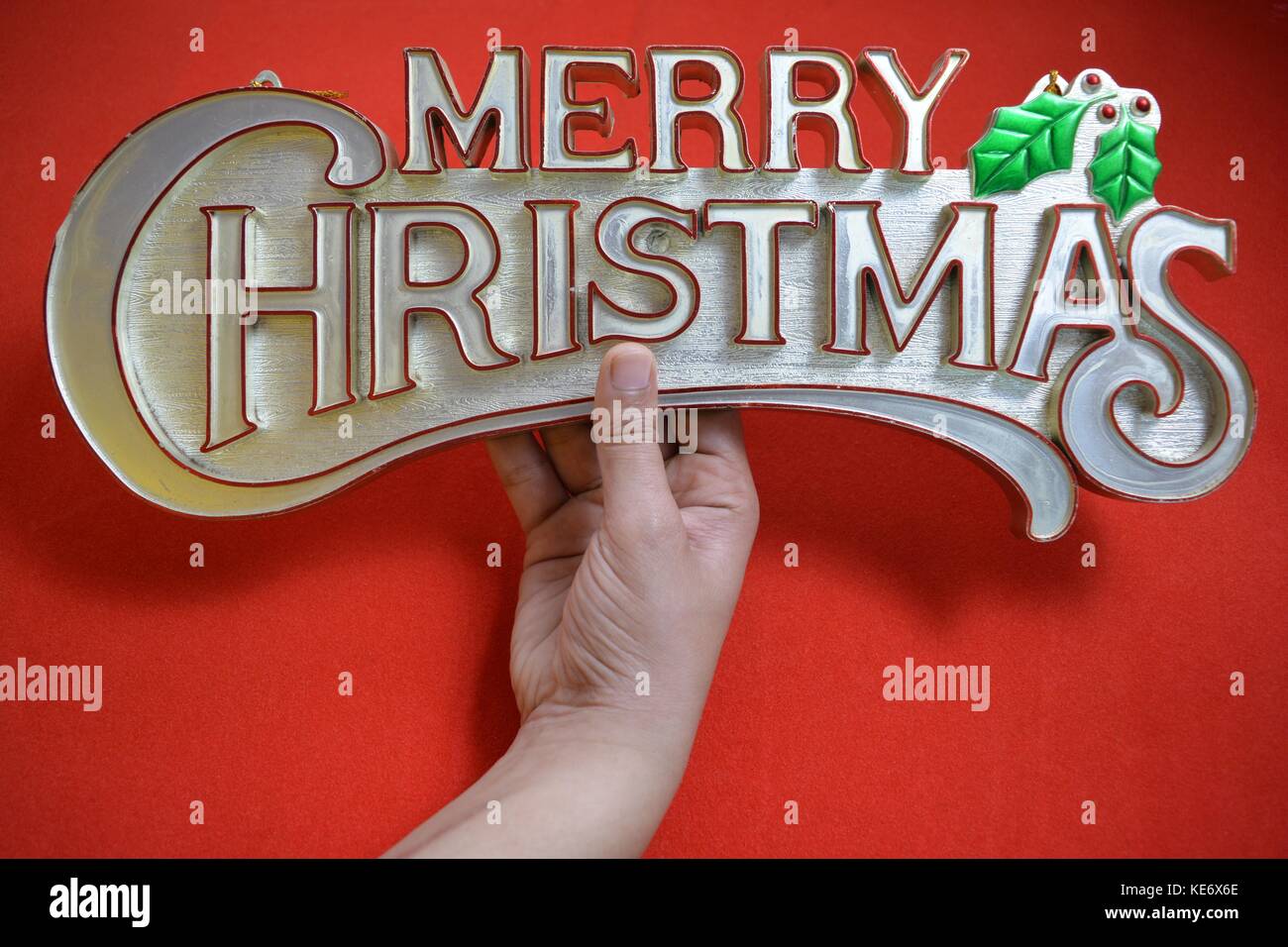 Merry Christmas in hand on red background Stock Photo - Alamy