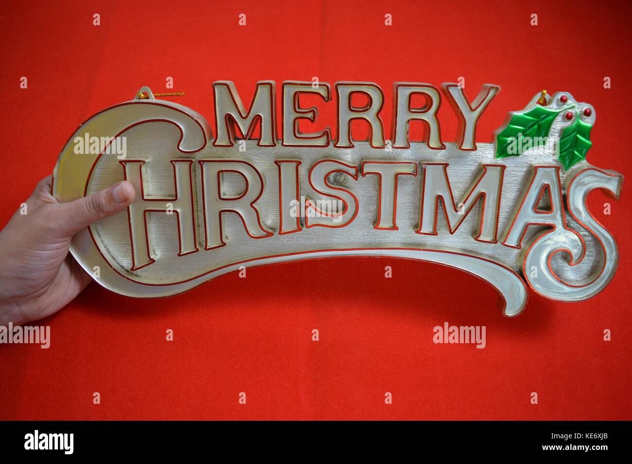 Merry Christmas in hand on red background Stock Photo - Alamy
