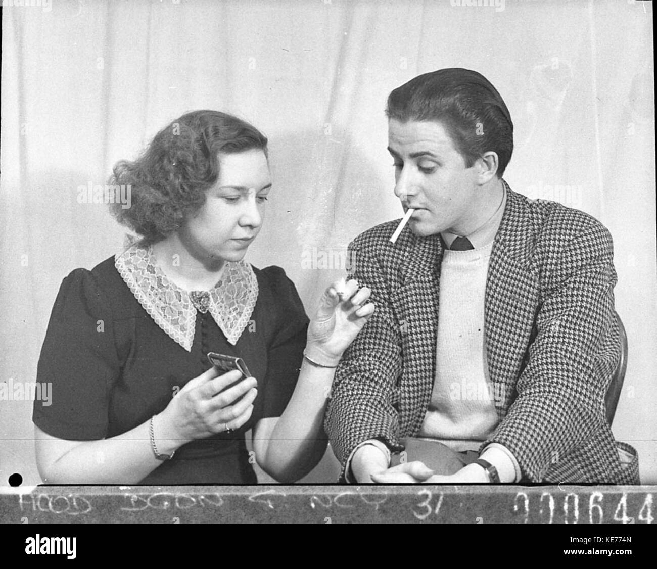 13144 An actress lighting an actors cigarette scene from These Children ...