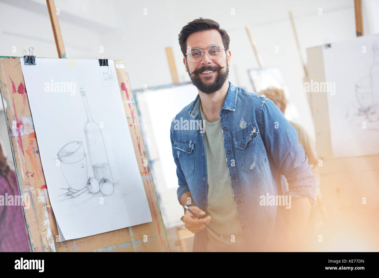 Portrait smiling male artist with beard sketching in art class studio ...
