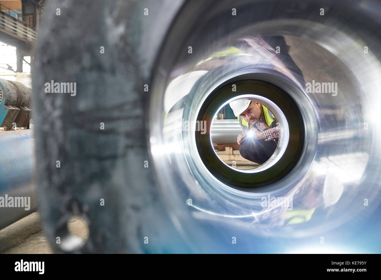 Male engineer with flashlight examining steel pipe in factory Stock ...