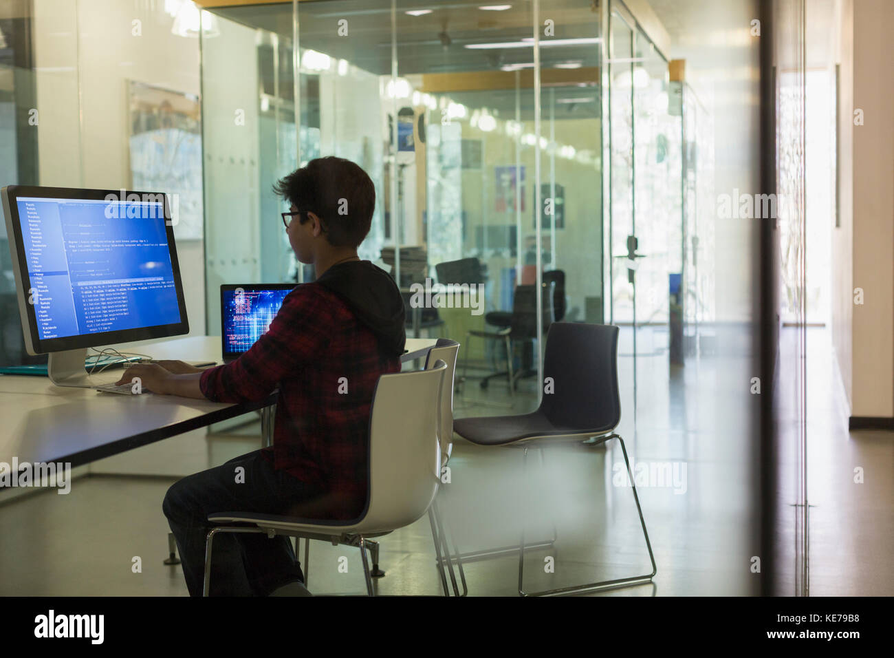 Focused boy student programming at computer in dark classroom Stock ...