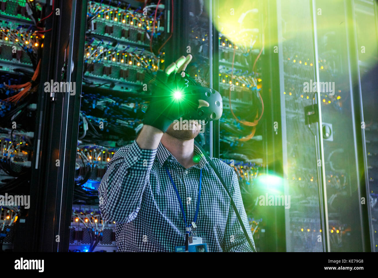 Male computer programmer using virtual reality simulator glasses and glowing glove in server ...