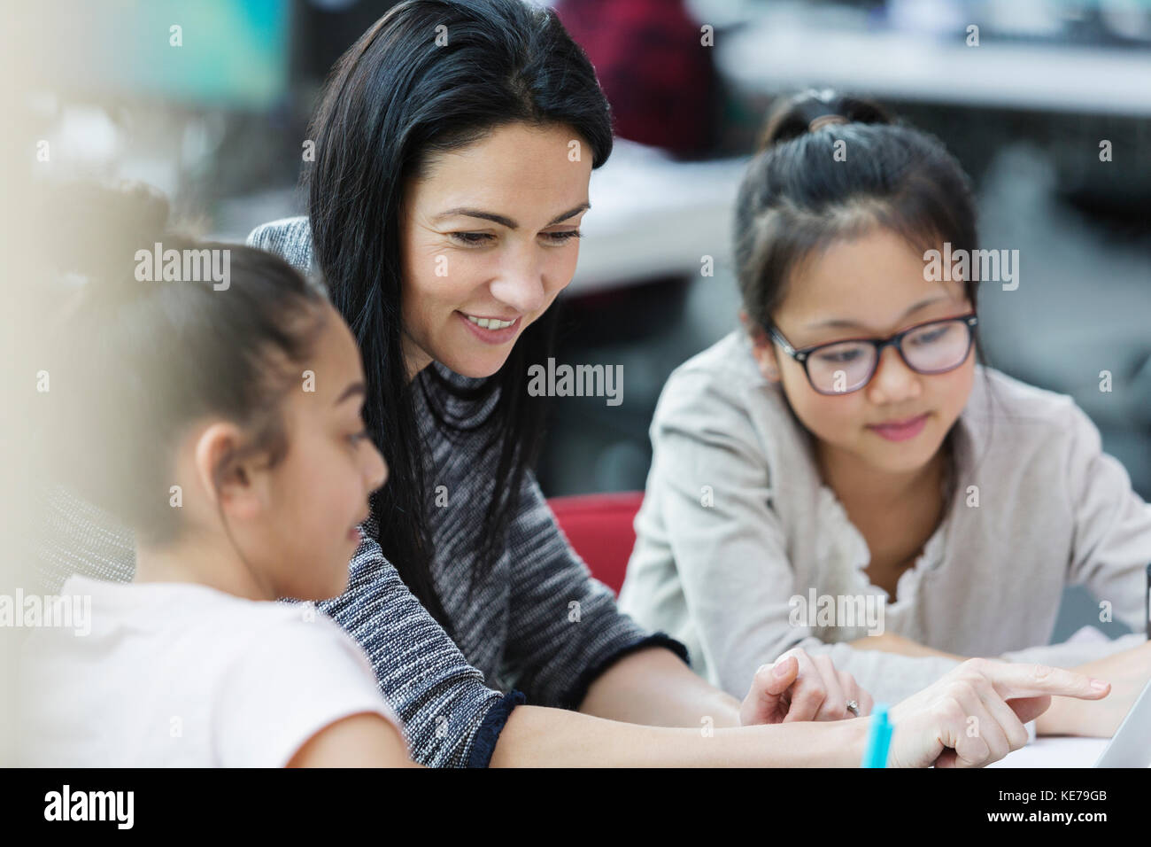 Female teacher and girl students using laptop in classroom Stock Photo ...