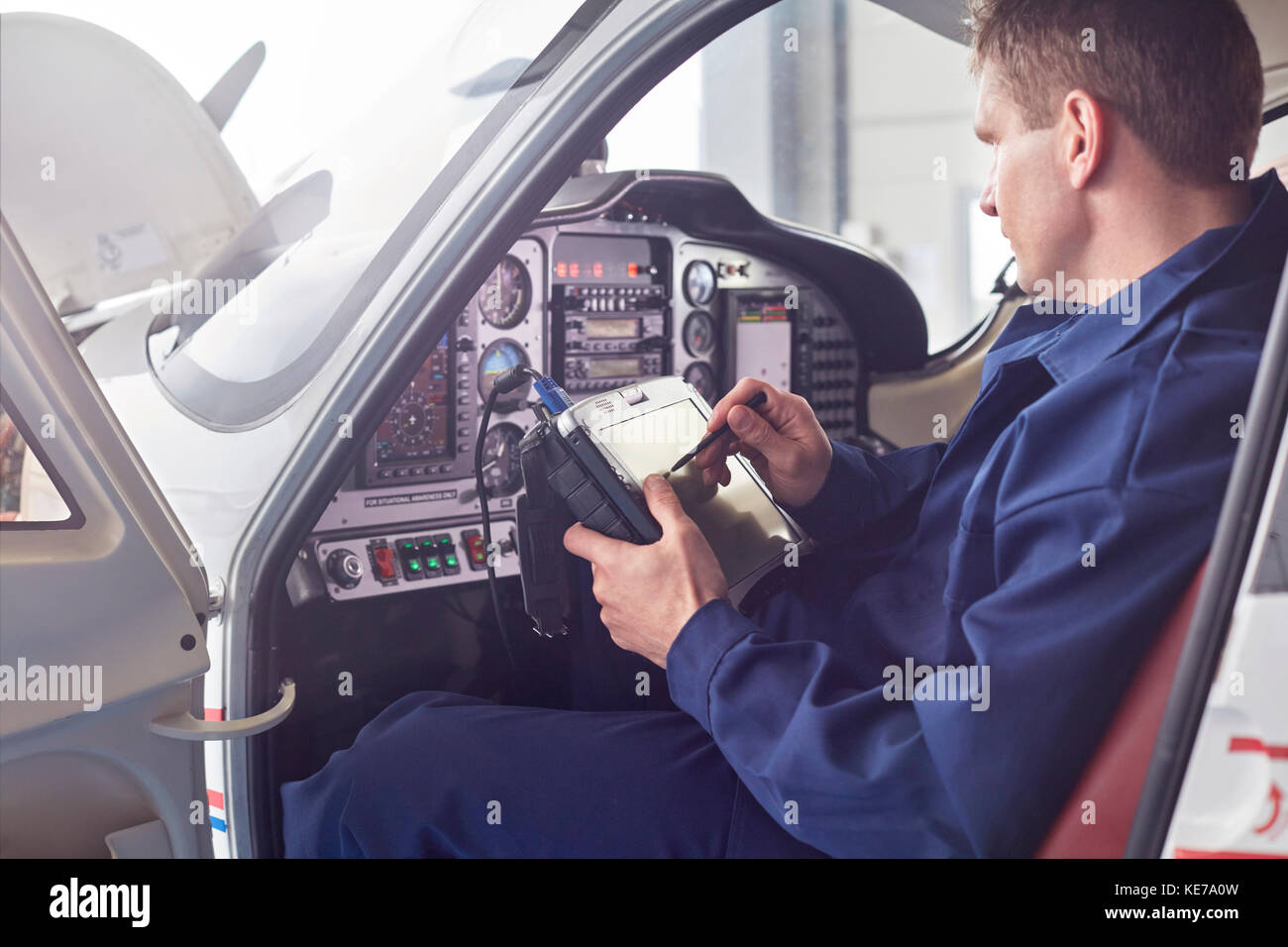 Male engineer checking diagnostics with digital tablet in airplane ...